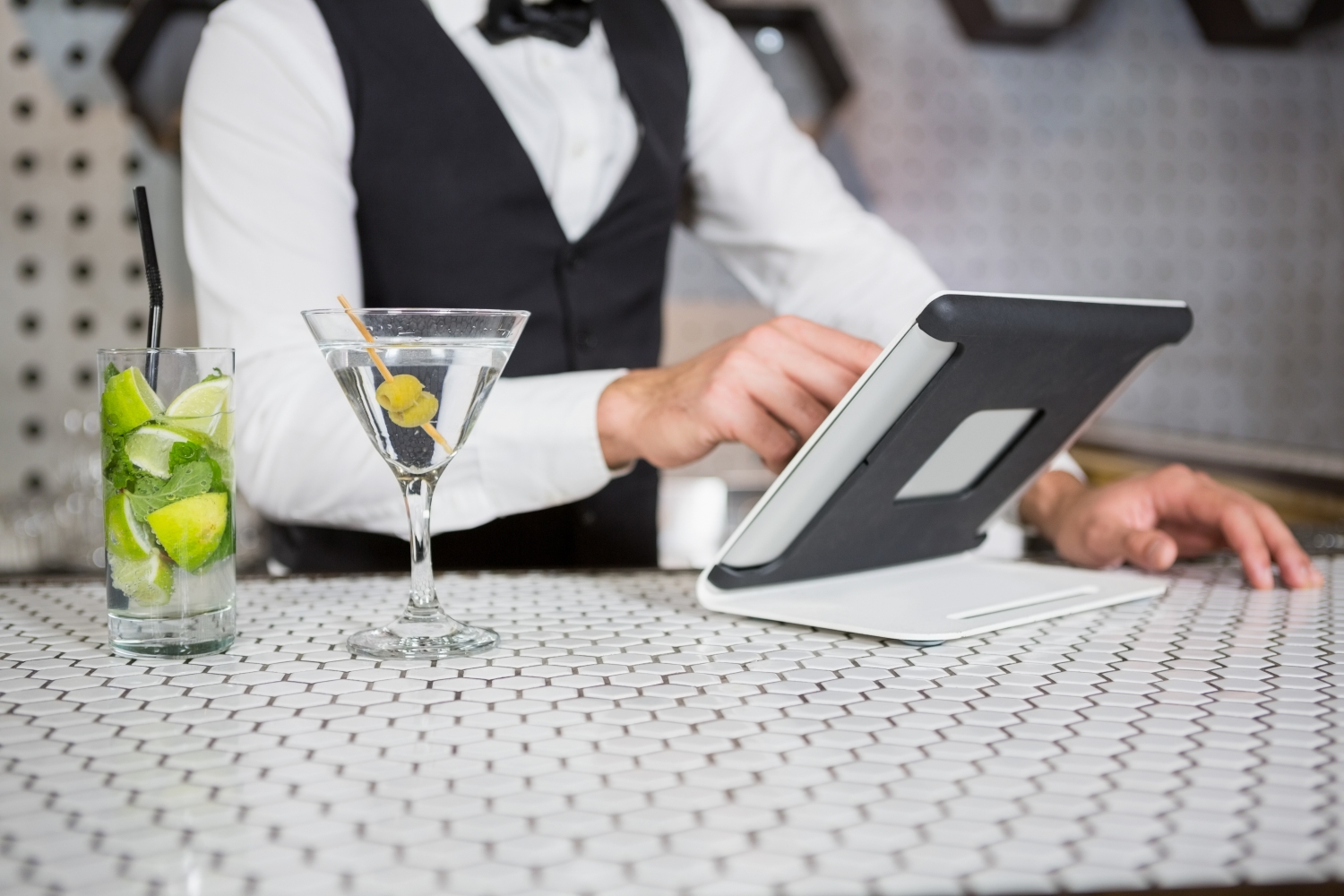 Bartender using digital tablet at bar counter - BARE International